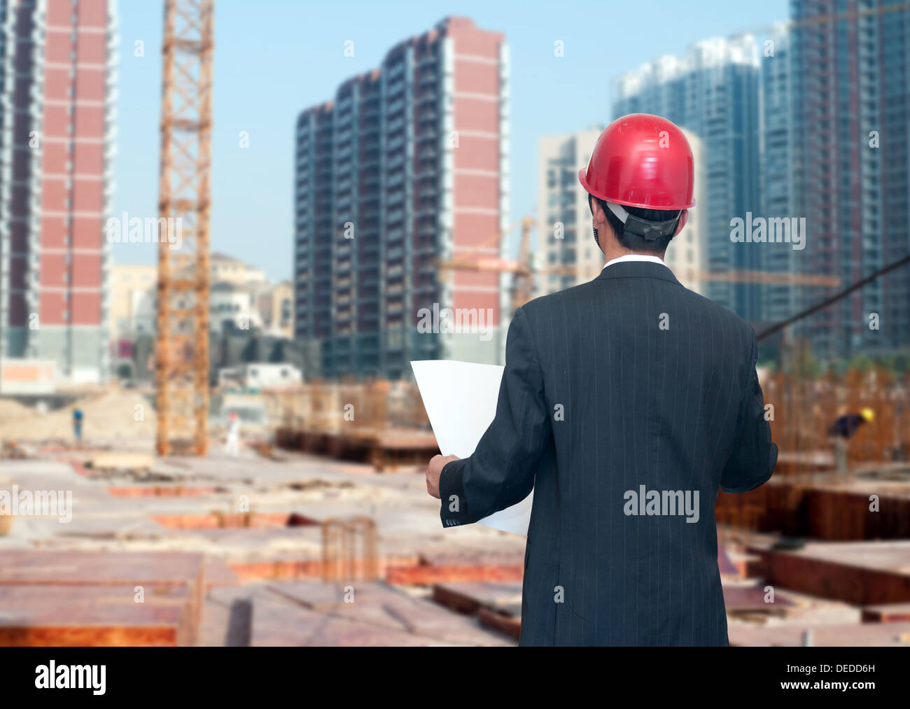 Rear view of architect looking comparing housing project with building ...