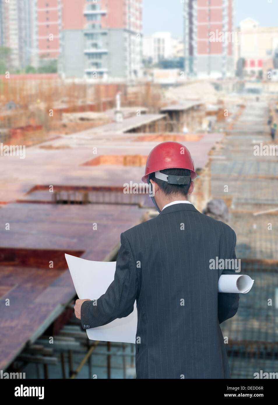Rear view of architect looking comparing housing project with building ...