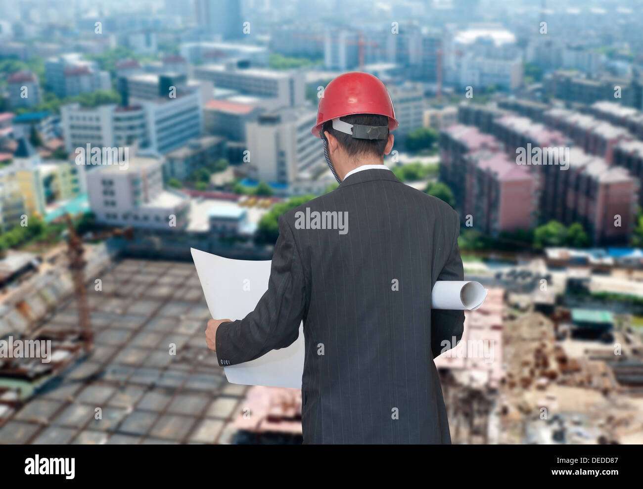 Rear view of architect looking comparing housing project with building ...