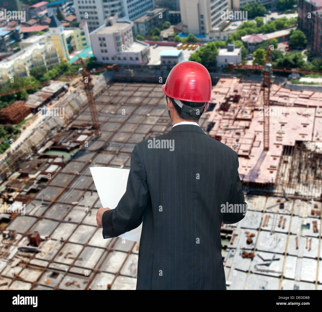 Rear view of architect looking comparing housing project with building ...