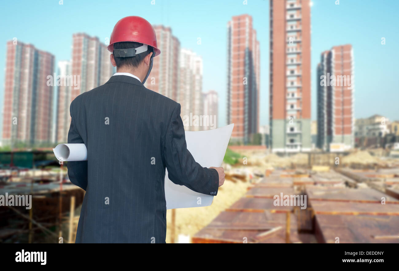 Rear view of architect looking comparing housing project with building ...