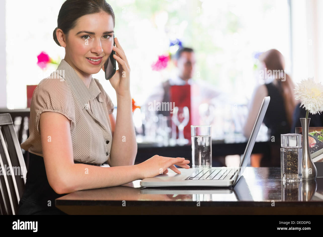 Businesswoman calling on phone using laptop Stock Photo - Alamy