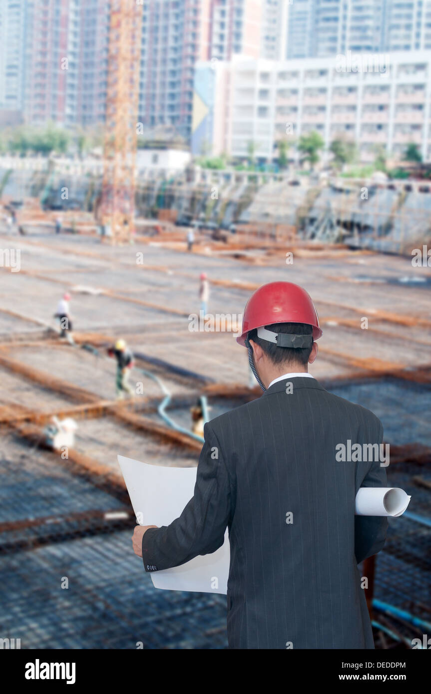 Rear view of architect looking comparing housing project with building ...
