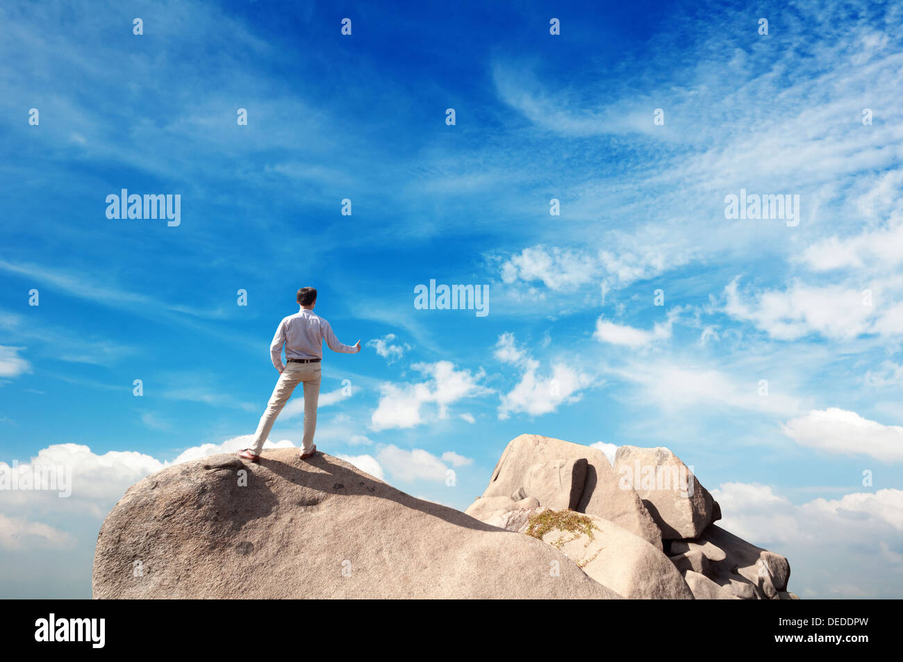 Young man standing on cliff's edge and looking into a wide valley Stock ...