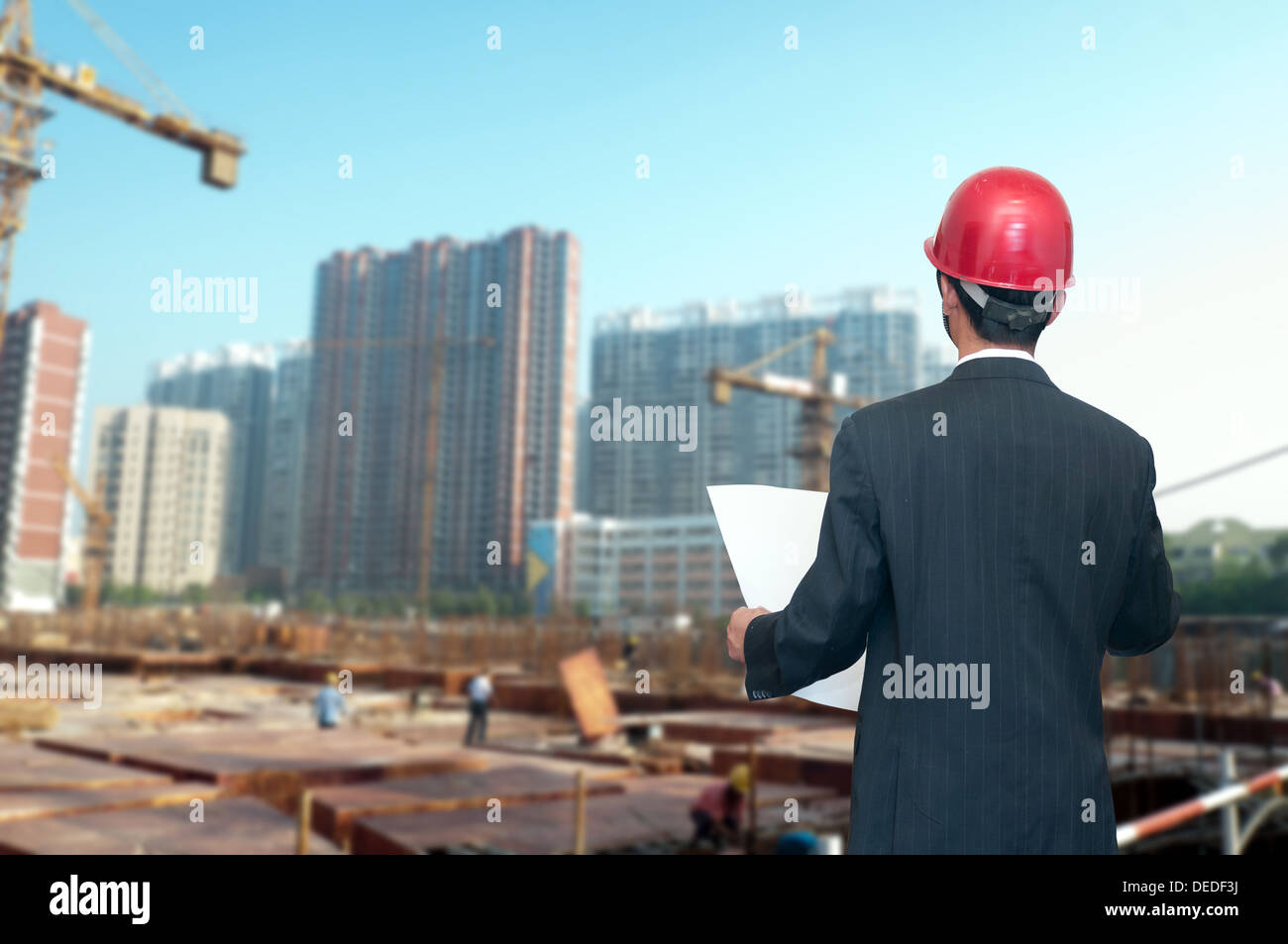 Rear view of architect looking comparing housing project with building ...