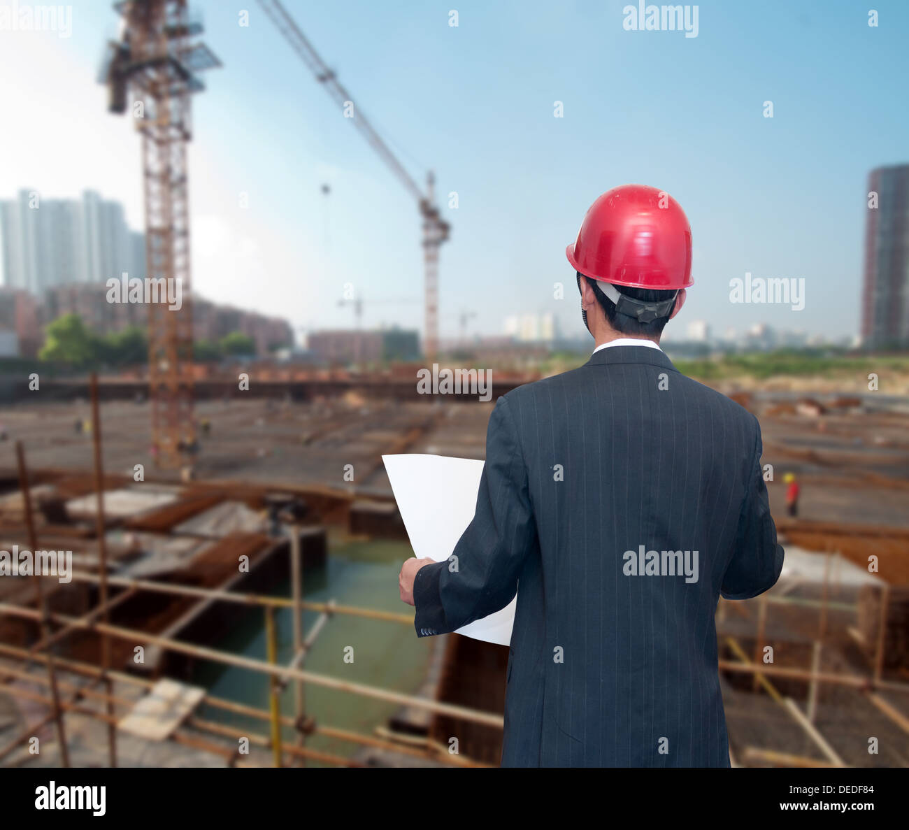 Rear view of architect looking comparing housing project with building ...