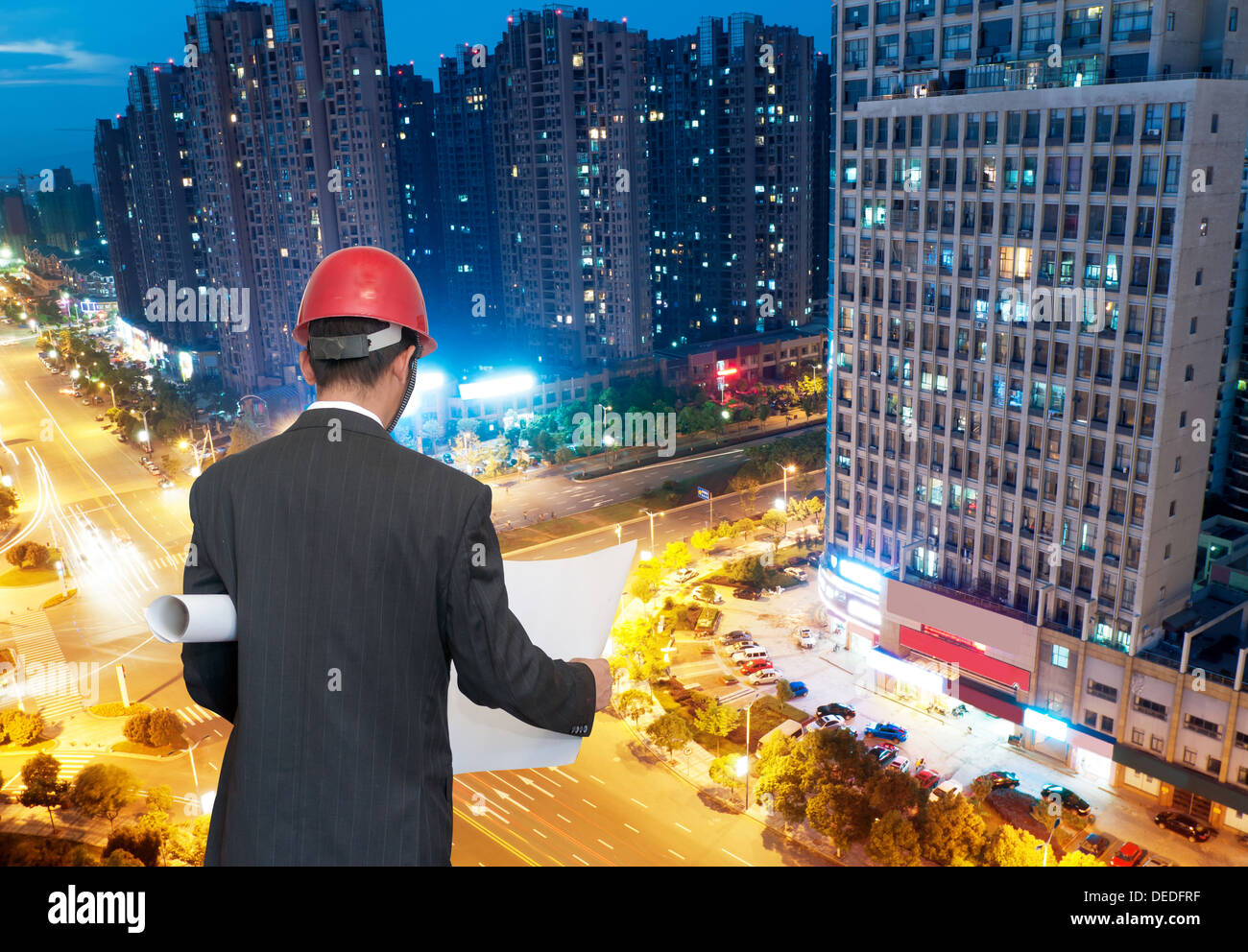Rear view of architect looking comparing housing project with building ...