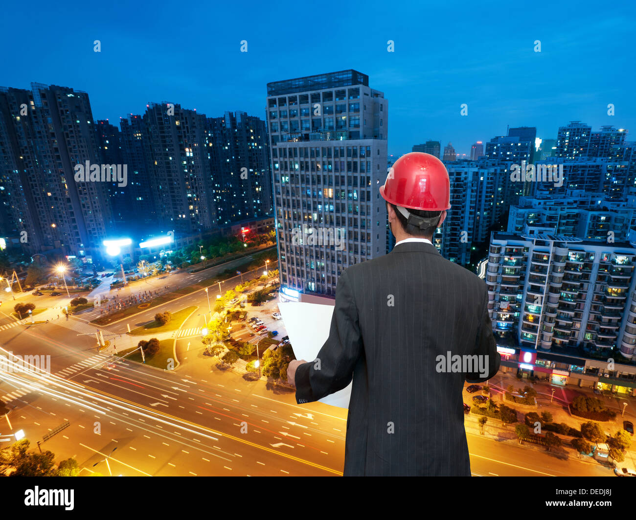 Rear view of architect looking comparing housing project with building ...