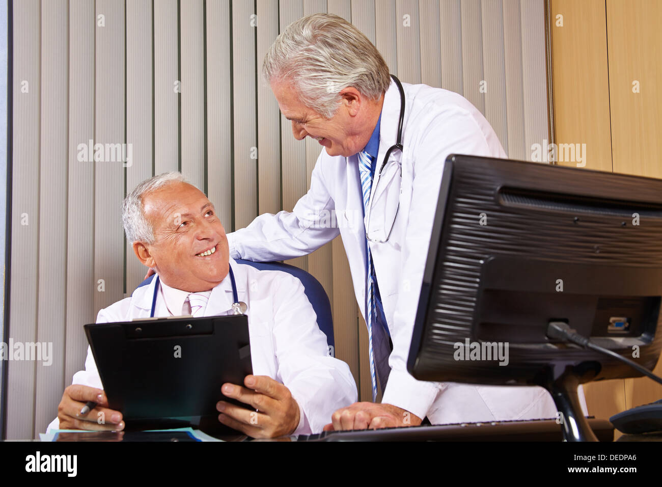 Two smiling senior physicians talking in a hospital office Stock Photo ...