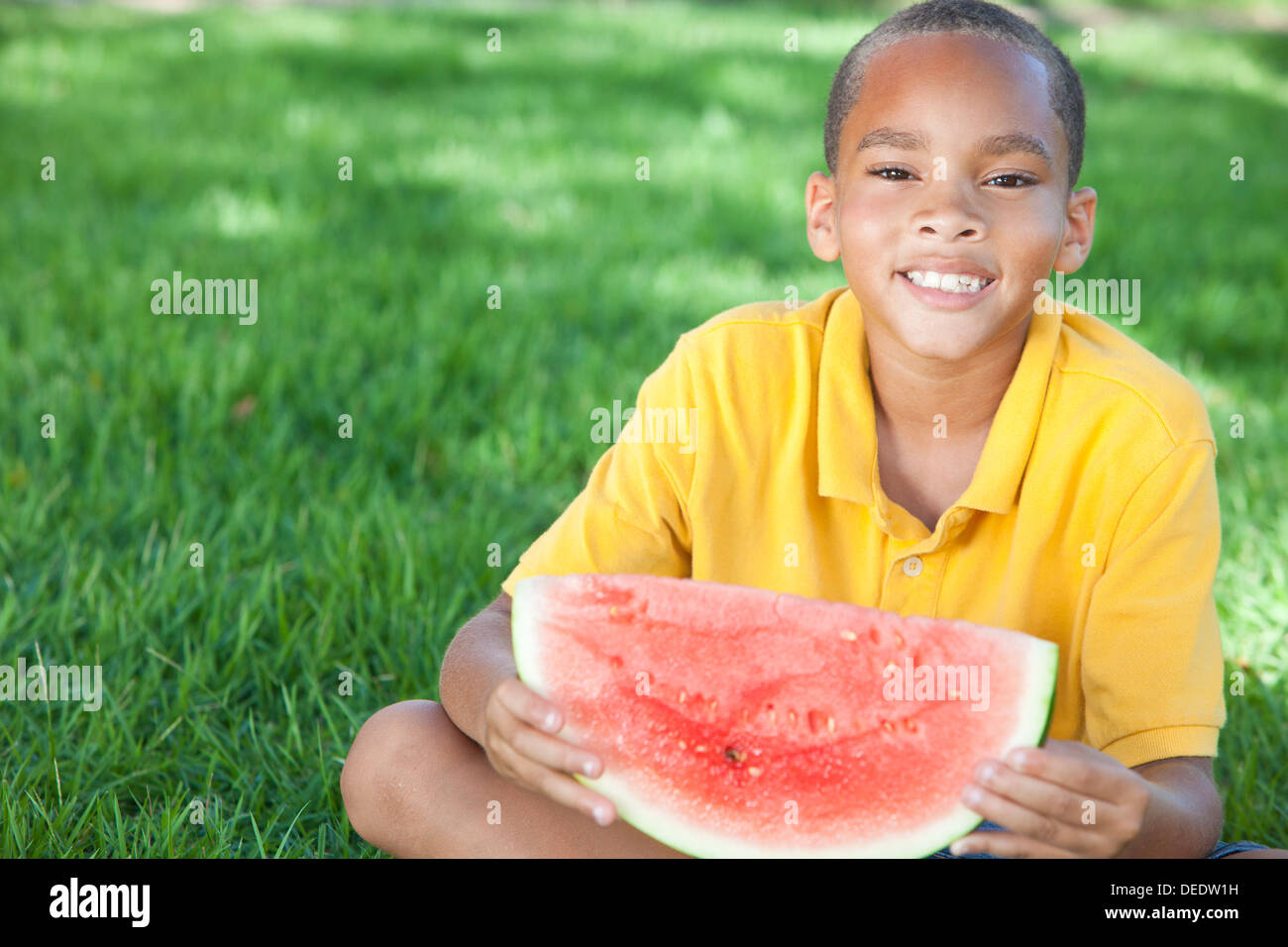 A cute, smiling & happy young African American boy child eating a slice ...