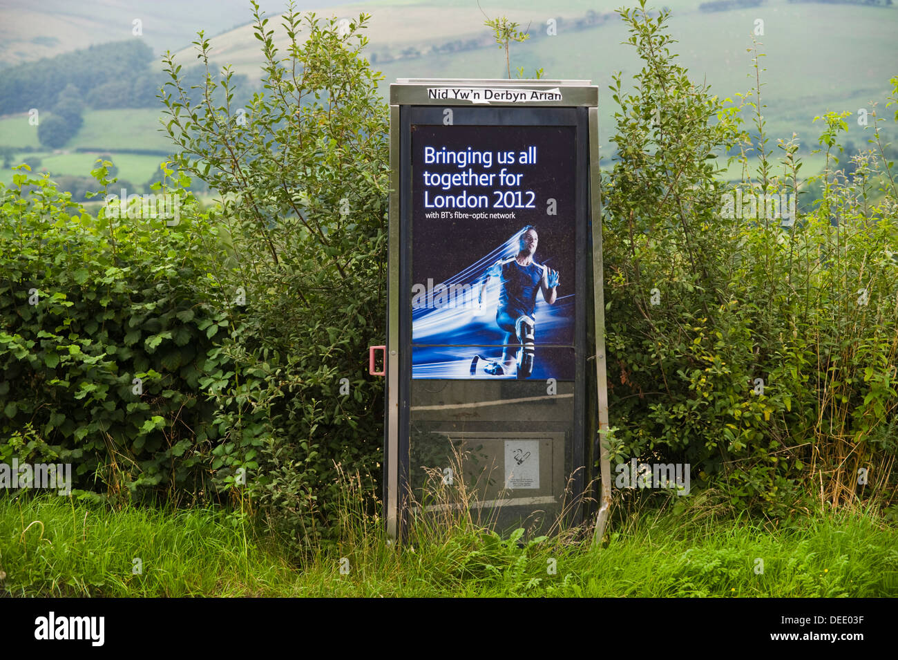 Derelict overgrown BT phone box advertising BT's fibre-optic broadband ...