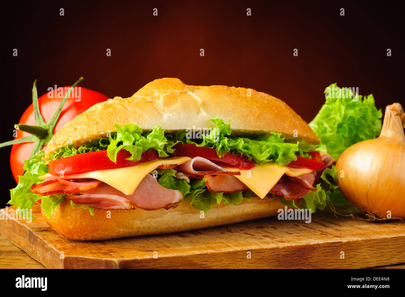 still life with delicious deli sub sandwich and vegetables Stock Photo ...