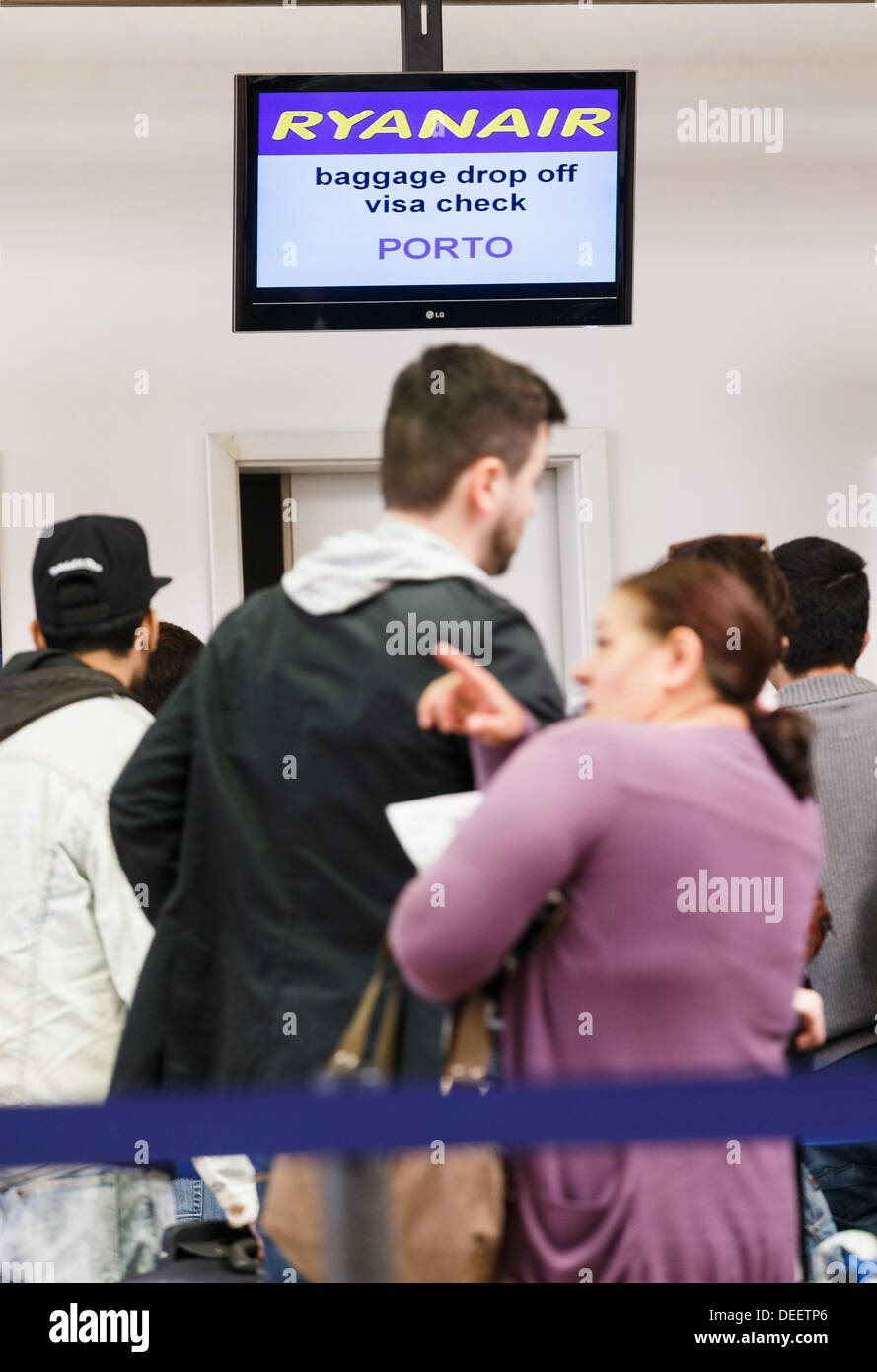 Passengers of a Ryanair flight queue at a check-in desk at the airport ...