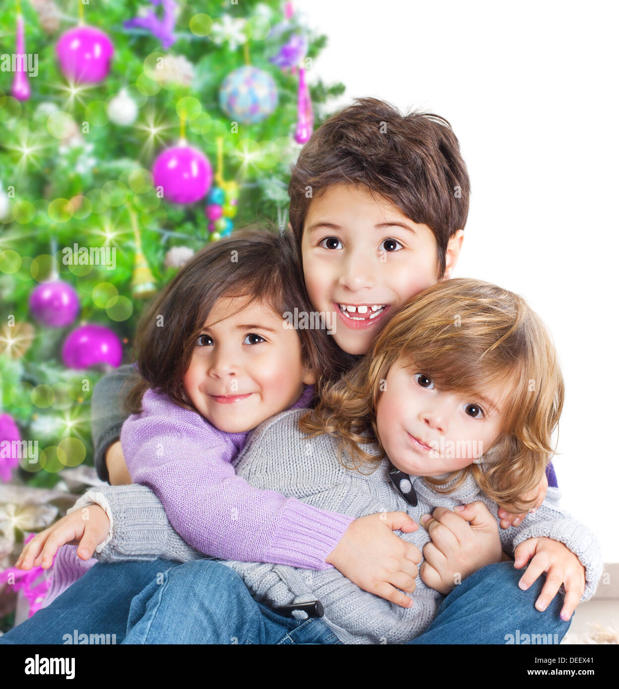 Happy kids near Christmas tree, three little friends enjoying New Year ...