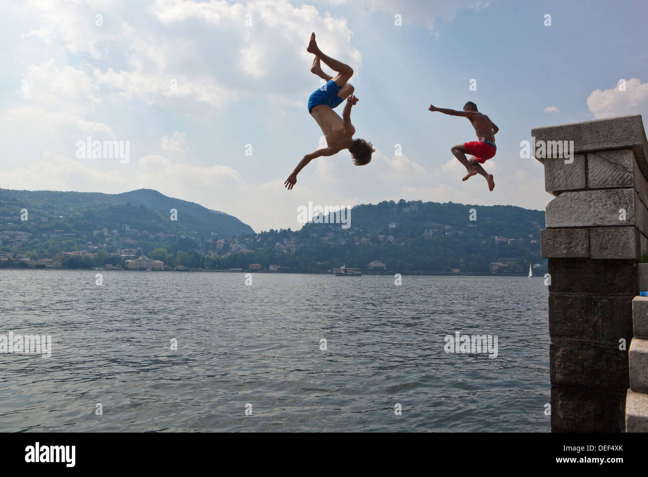 Two airbourne young men dive into a lake Stock Photo - Alamy