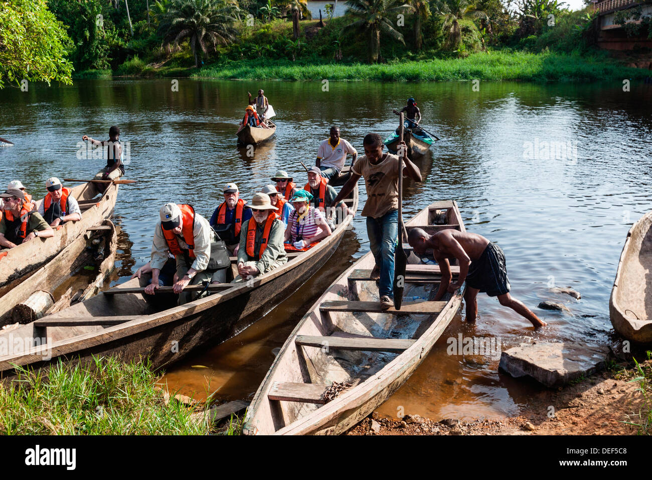 Africa, Cameroon, Kribi. Tourists gathered in traditional pirogue ...