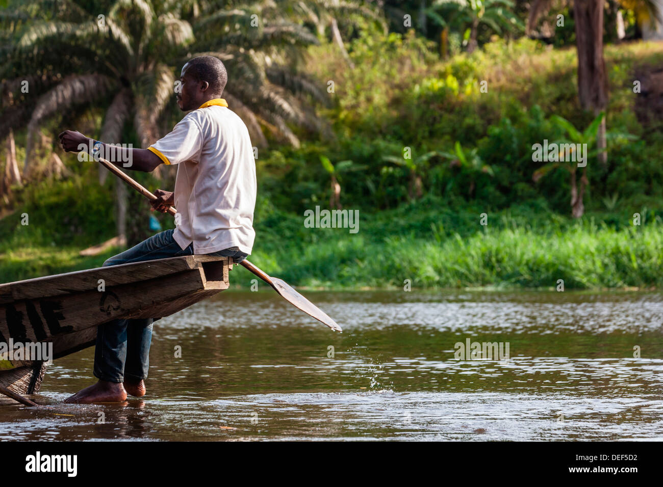 Africa, Cameroon, Kribi. Man rowing traditional pirogue boat down Lobe ...