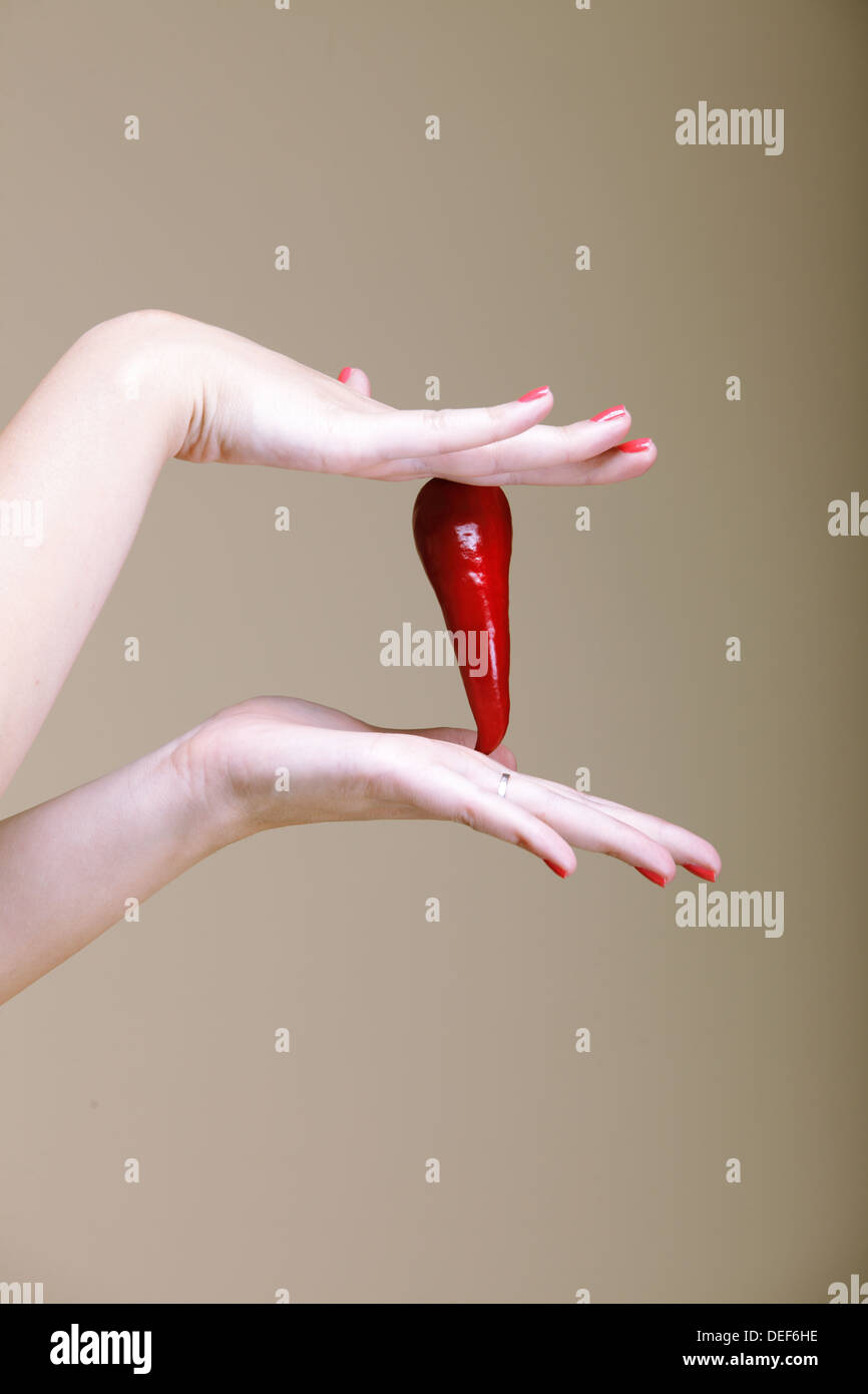 chili pepper in female hand brown background Stock Photo - Alamy