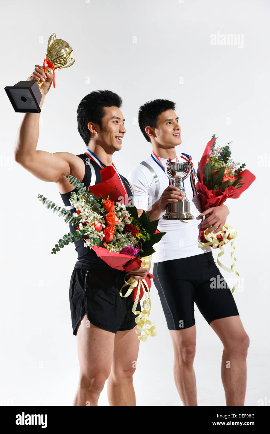 Two young athletes holding trophy and flowers Stock Photo - Alamy