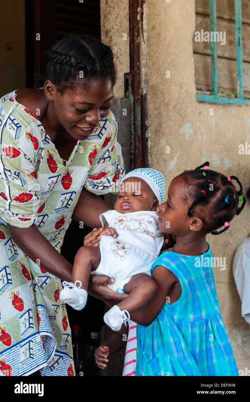 Africa, Gabon, Libreville. Mother handing baby to daughter to hold ...