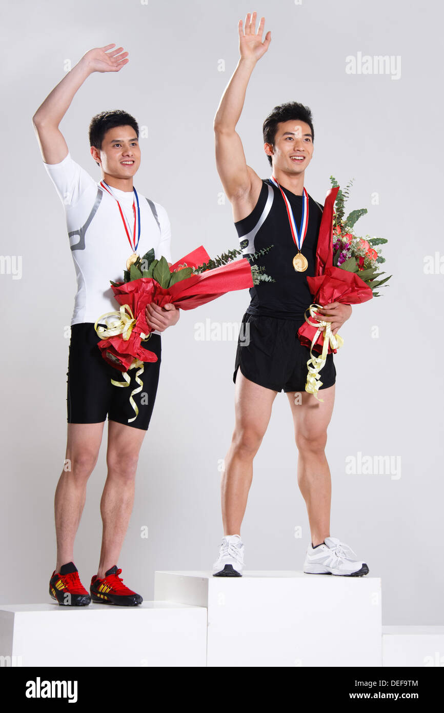 Portrait of two young men standing on a winners podium and wearing ...