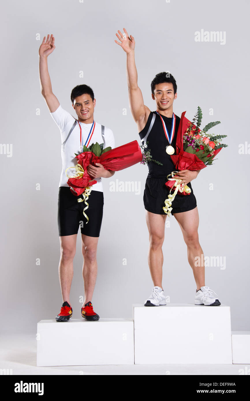 Portrait of two young men standing on a winners podium and wearing ...