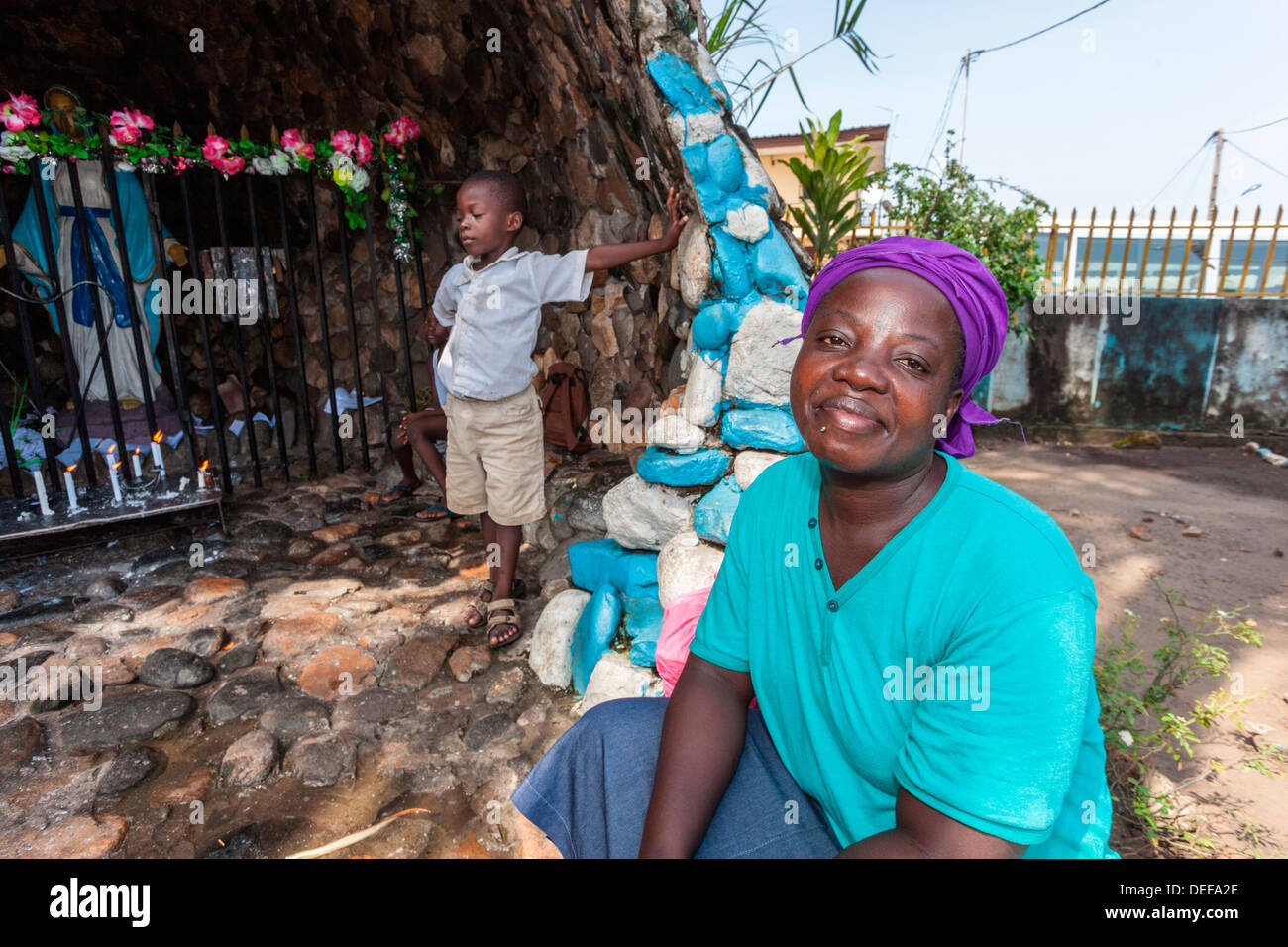 Africa, Gabon, Libreville. Mother and child worshipping at grotto ...