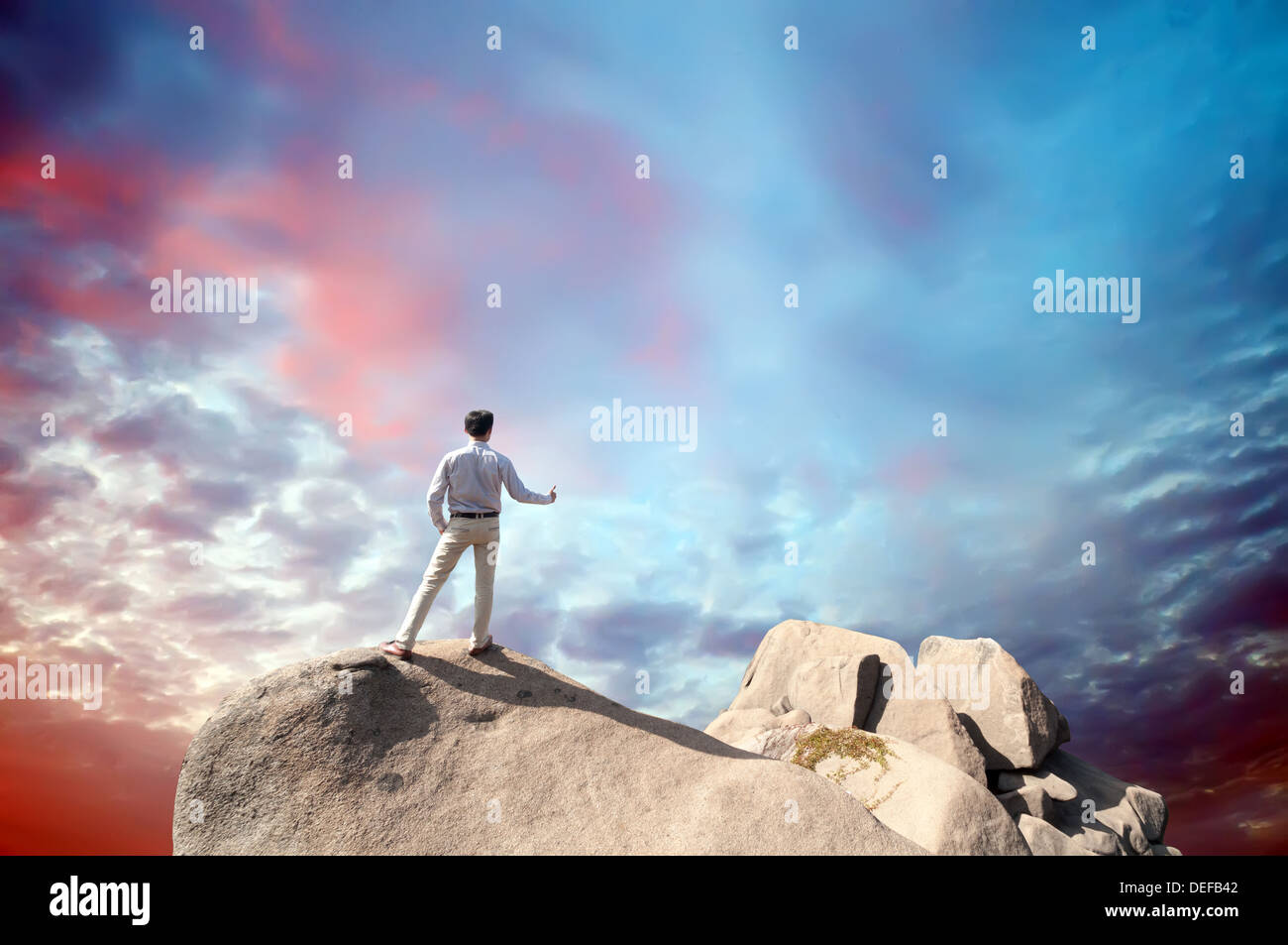Young man standing on cliff's edge and looking into a wide valley Stock ...