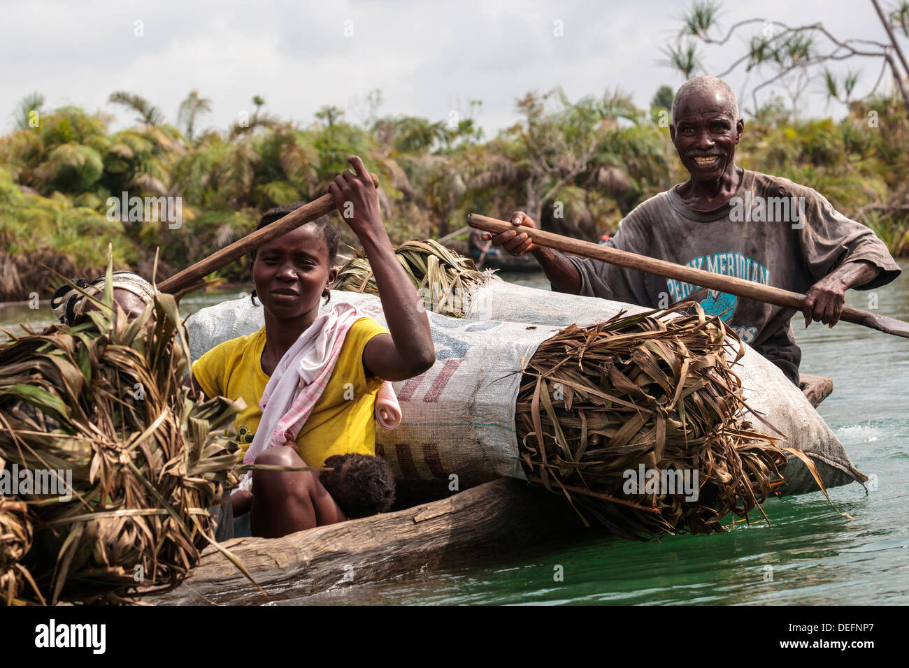 Africa, Liberia, Monrovia. Family transporting bundles of dried ...