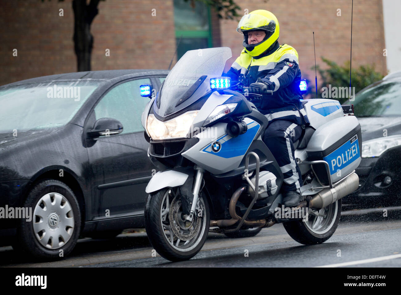 A motorcycle police officer in the new blue uniform drives outside of ...