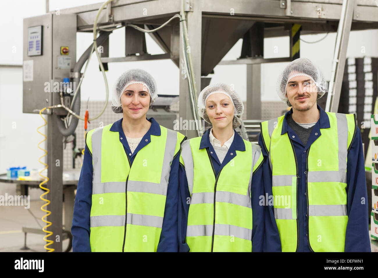 Young people working in Industrial Factory preparing food for packing ...