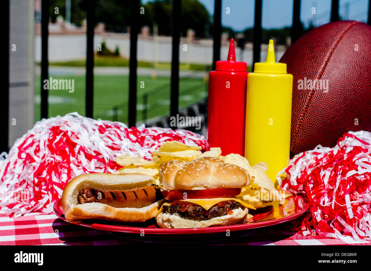 Tailgating party with cheeseburger, hot dog, potato chips, pom poms ...
