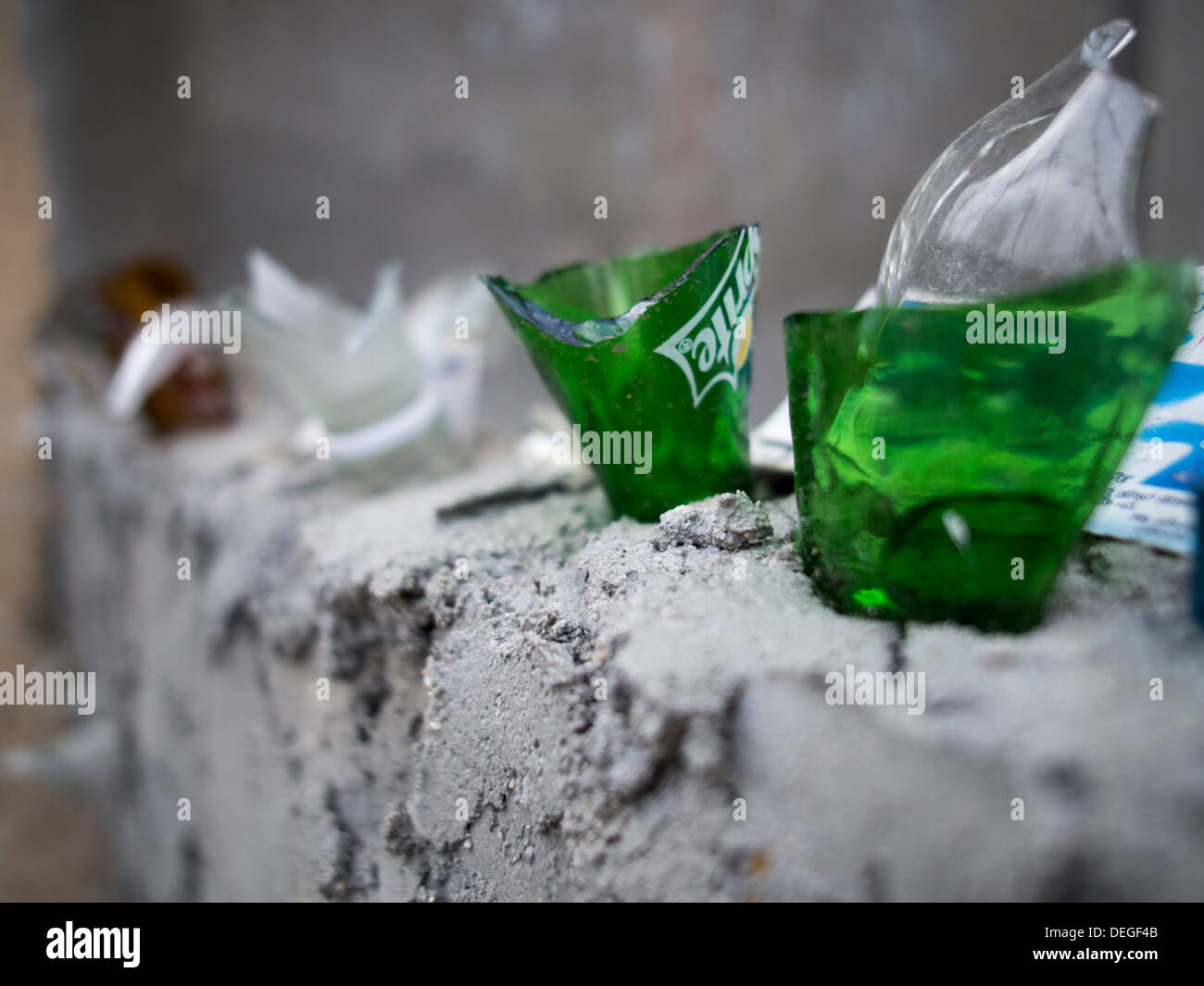 Shards of glass beer bottles stick out at the top of a concrete wall in ...