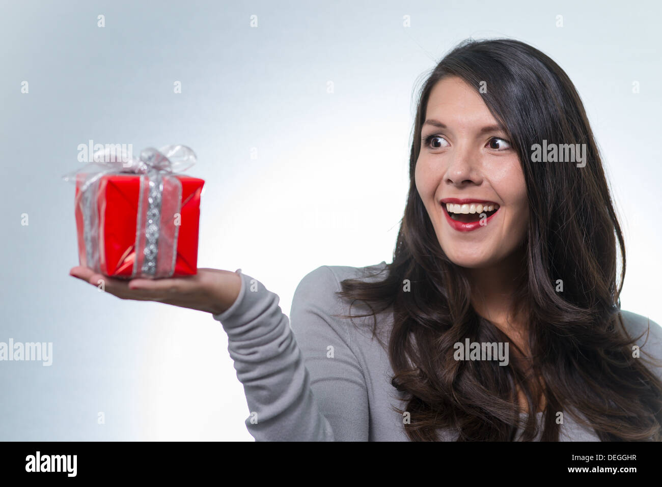 Beautiful romantic woman eying a red wrapped gift Stock Photo - Alamy