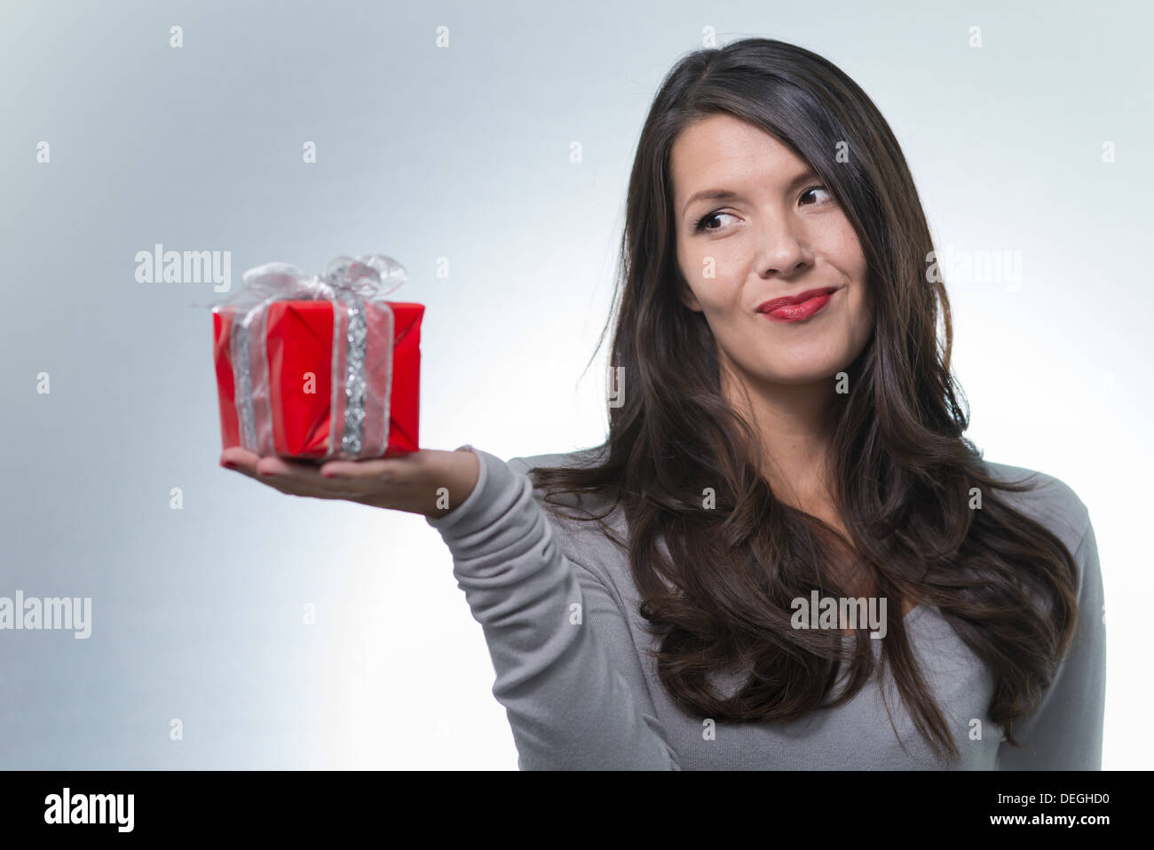 Beautiful romantic woman eying a red wrapped gift Stock Photo - Alamy