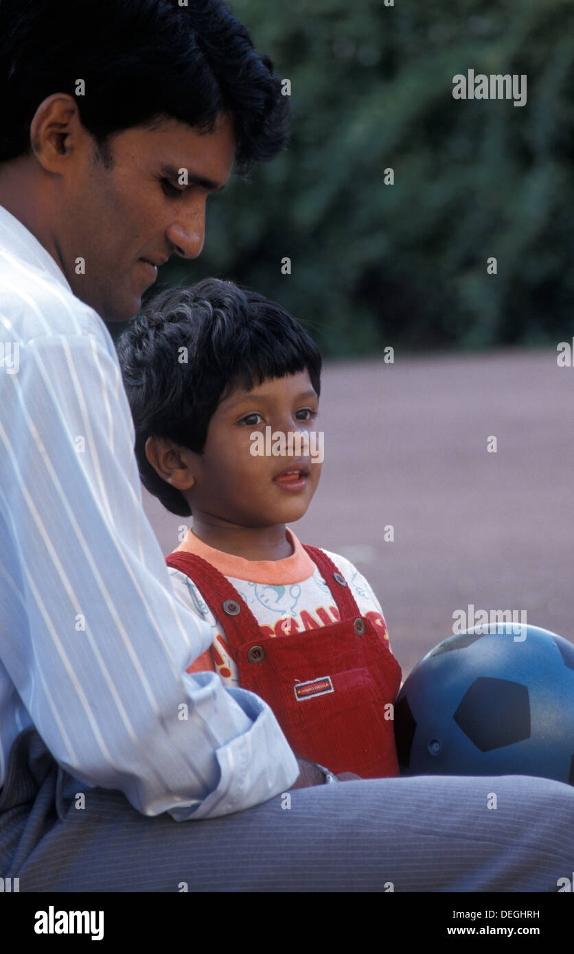 dark skinned father and toddler son sitting on park bench Stock Photo ...