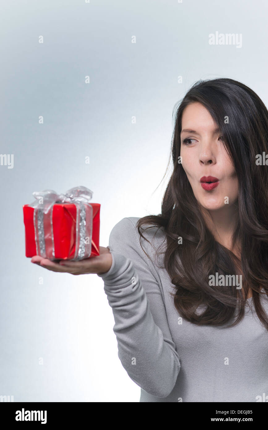 Beautiful romantic woman eying a red wrapped gift Stock Photo - Alamy