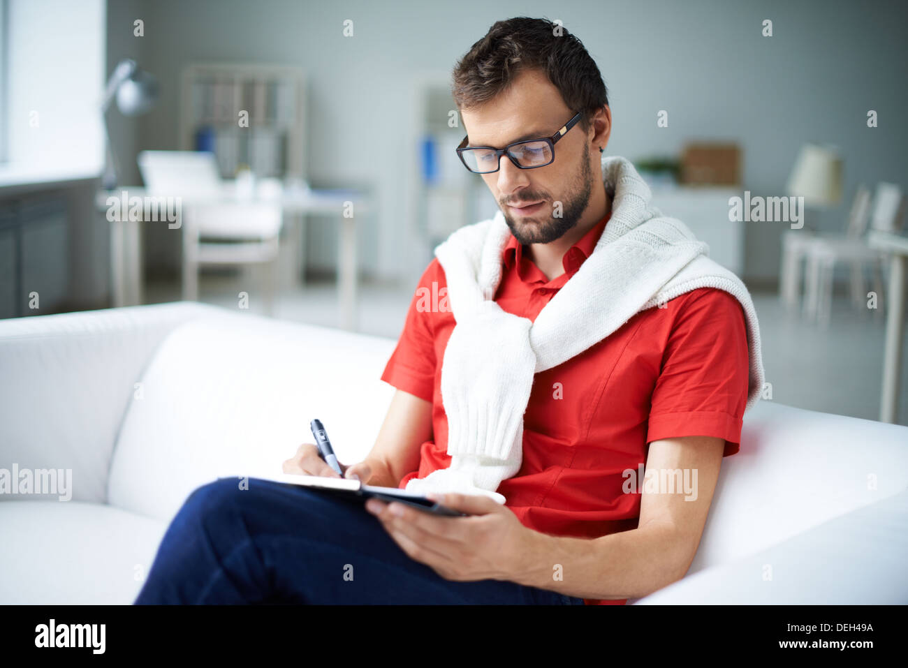 Smart businessman making notes while sitting on sofa in the office ...
