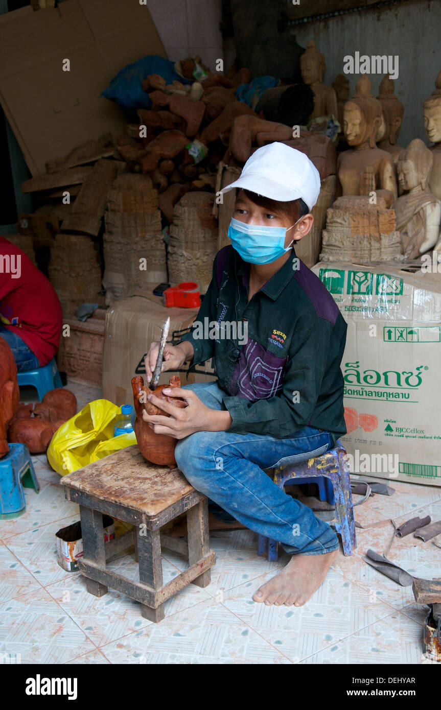 Child labor, a young boy wearing a pollution mask works at a wood ...