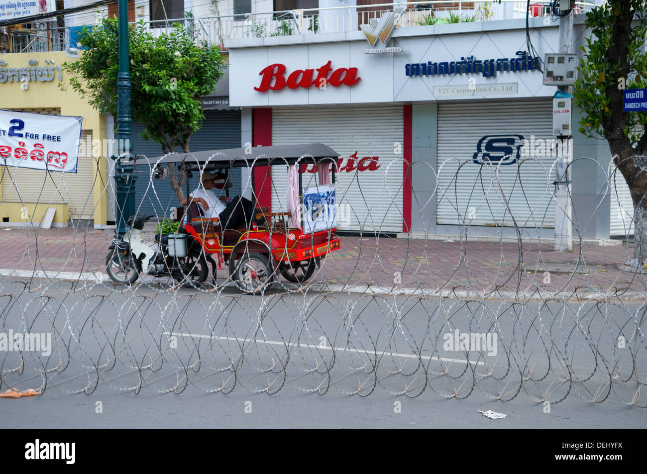 A tuk tuk behind a razor wire barricade in the city of Phnom Penh ...