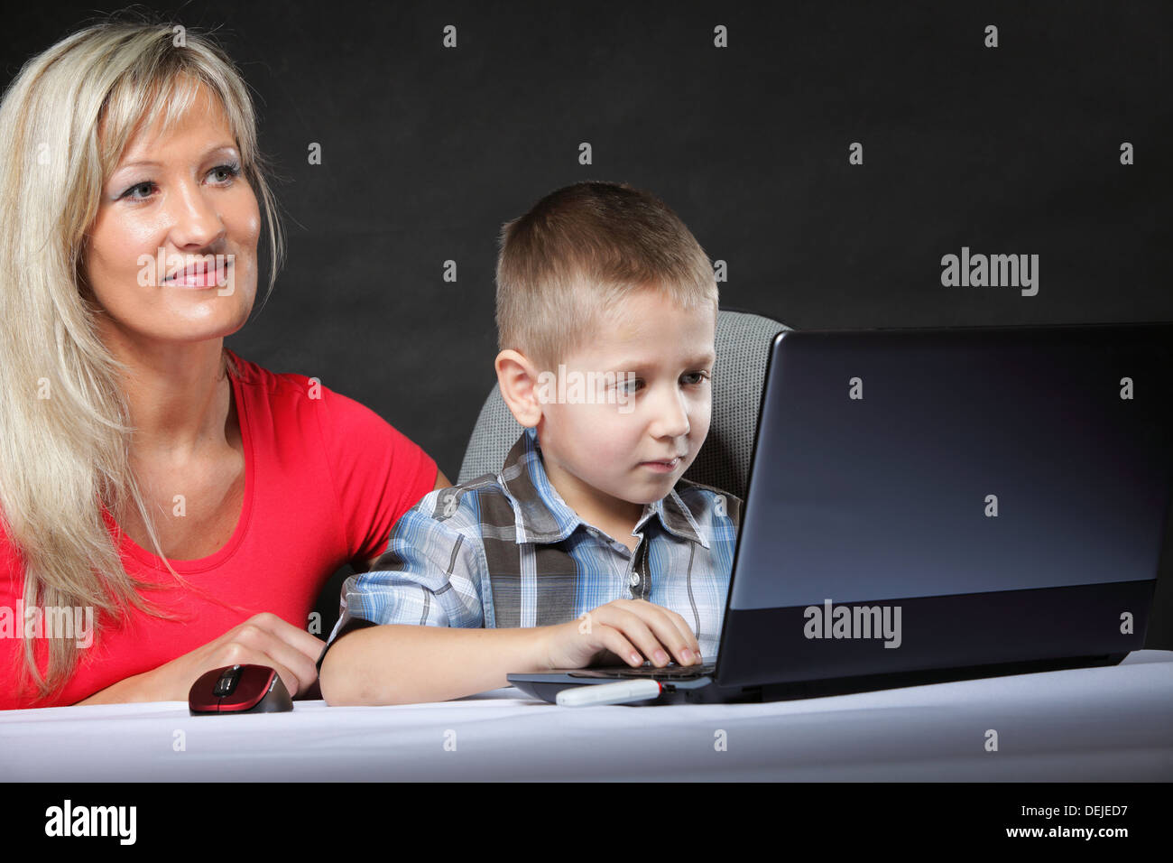 mother with son together looking on the laptop computer black ...