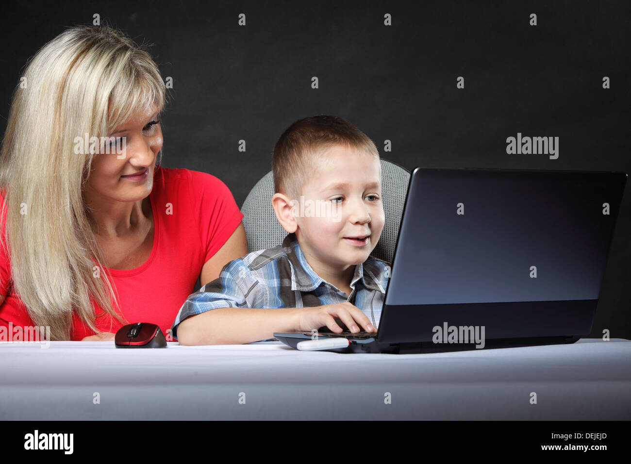 mother with son together looking on the laptop computer black ...