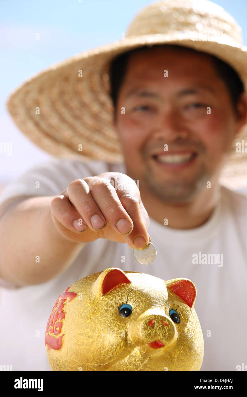 Farmer putting coin in piggy bank Stock Photo - Alamy
