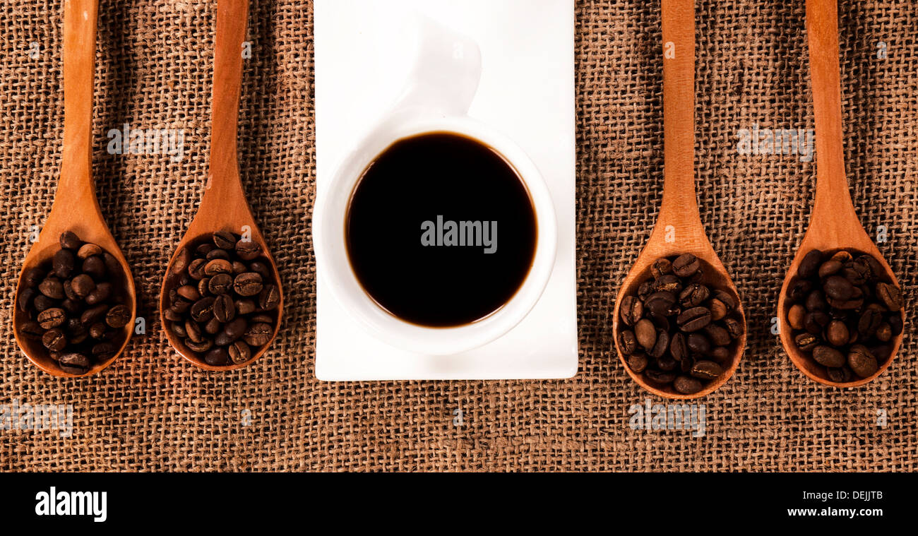 Dark coffee in the cup and raw beans in spoons from above Stock Photo ...