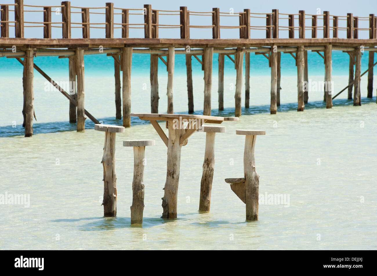 Long wooden jetty on a tropical island stretching out into the sea with ...