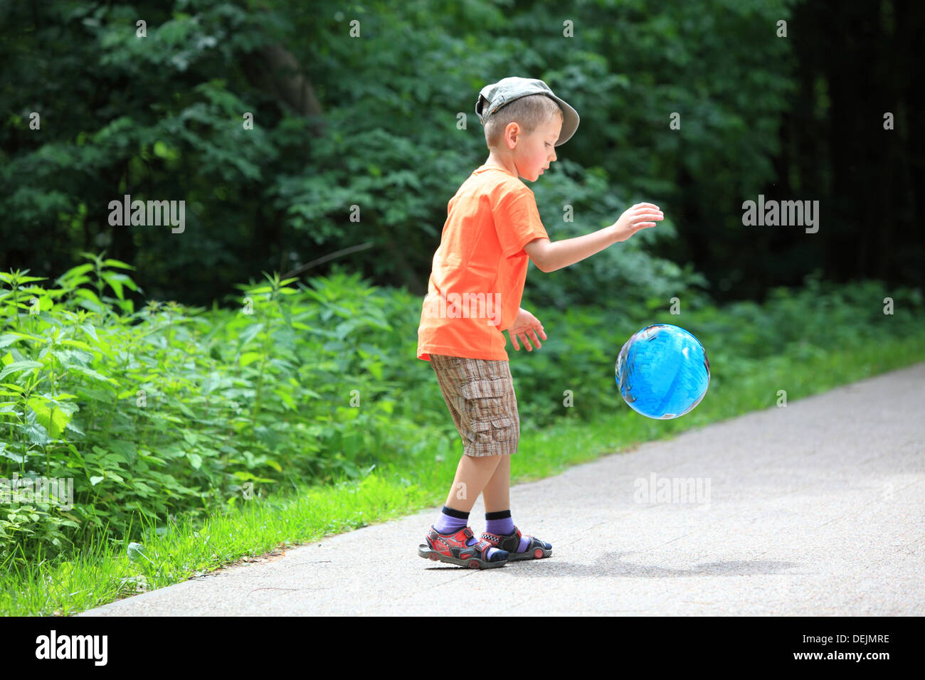 Boy in action young kid playing with ball in park outdoors. Healthy ...