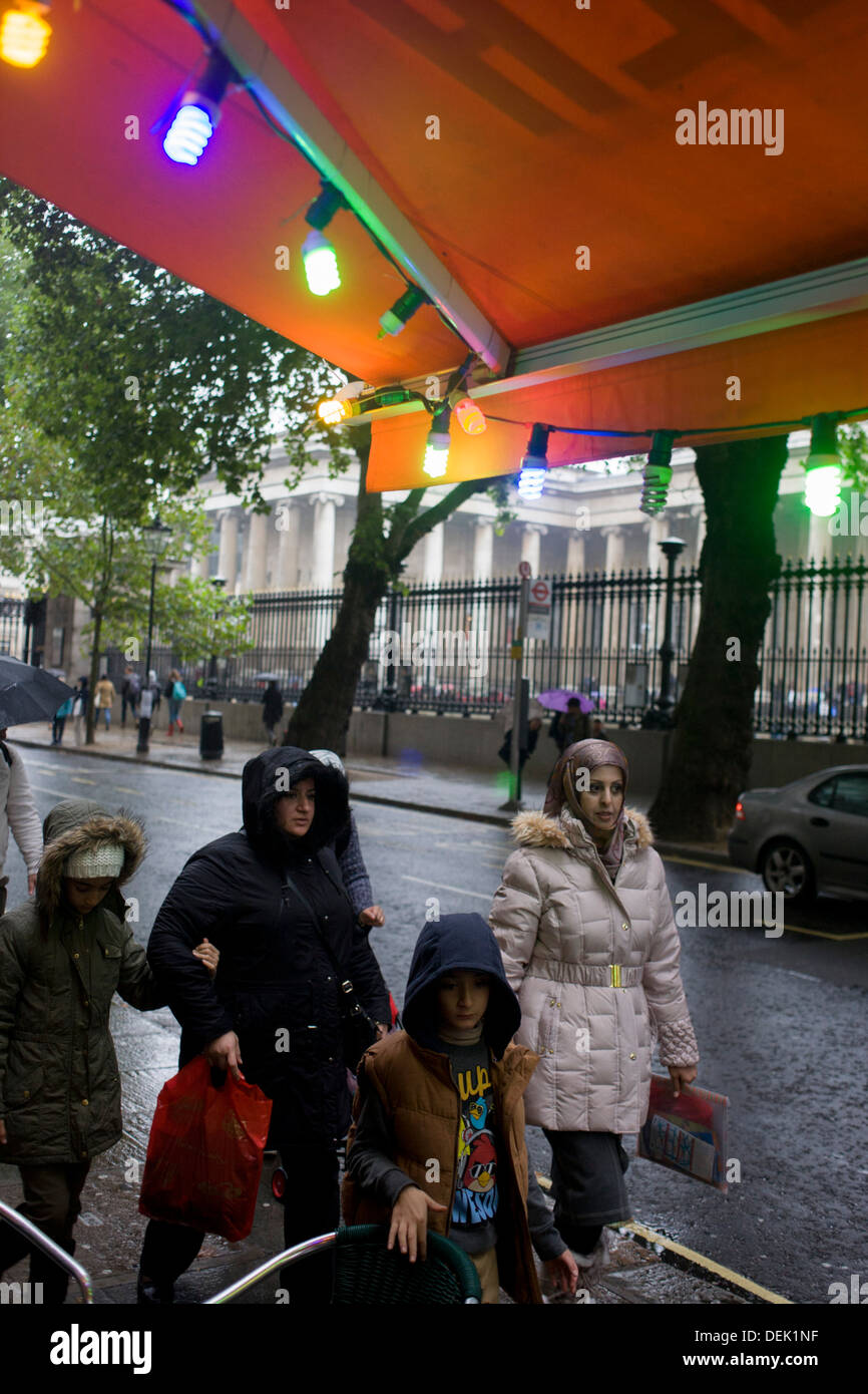A family walk beneath coloured lights during damp, gloomy weather in ...