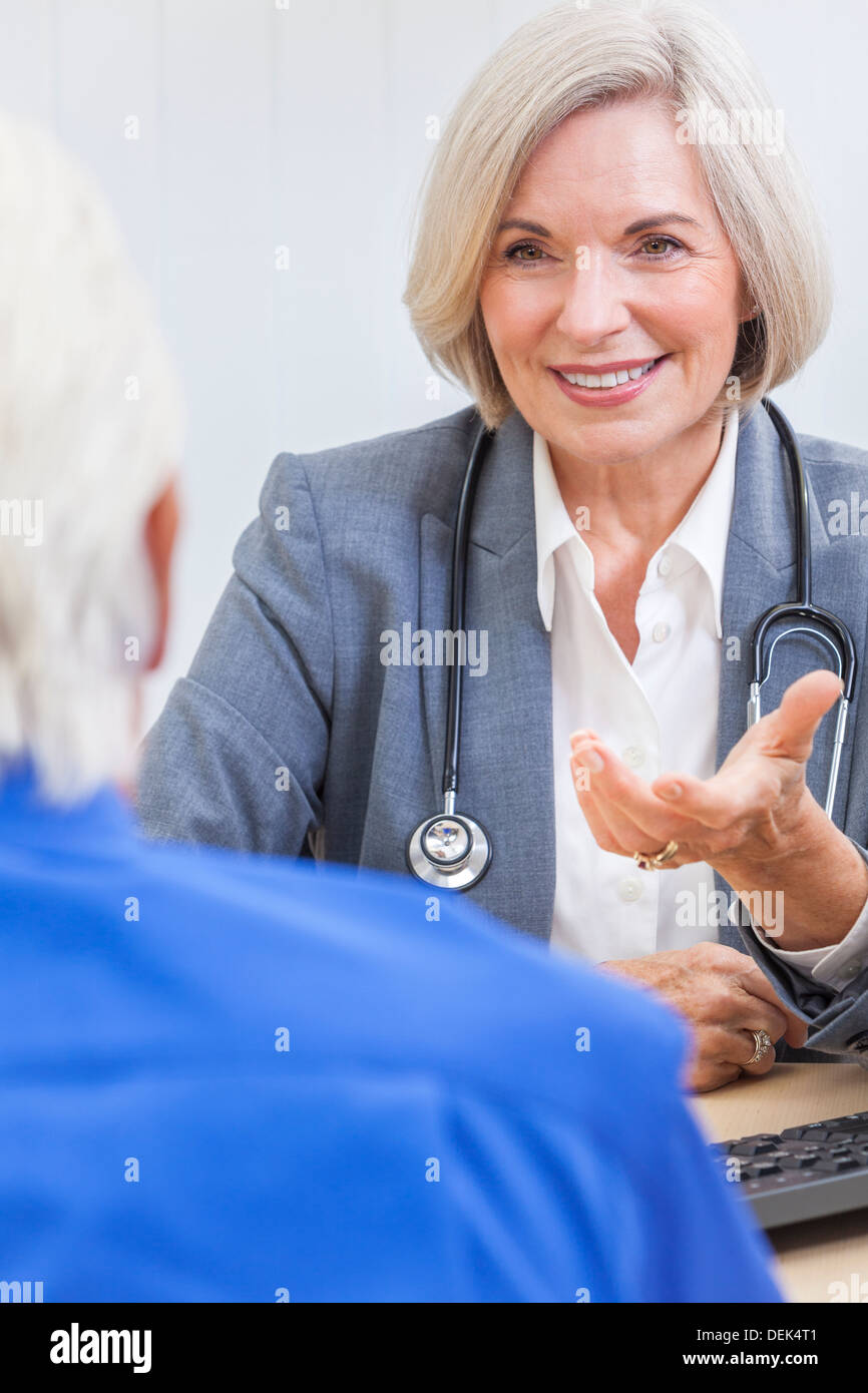 A senior female woman doctor sitting at a desk wearing a suit and ...