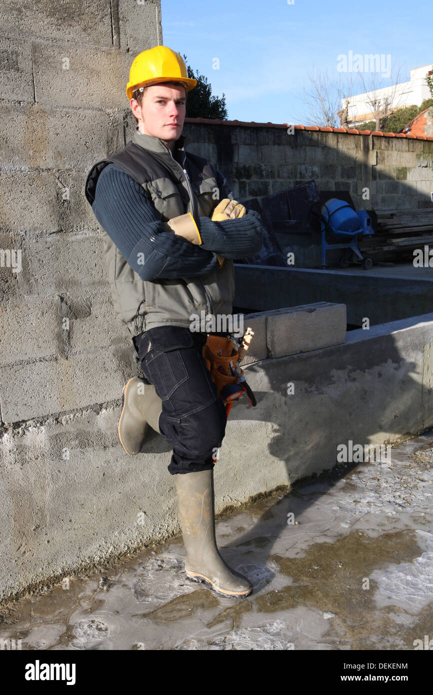 Builder casually leaning against wall Stock Photo - Alamy
