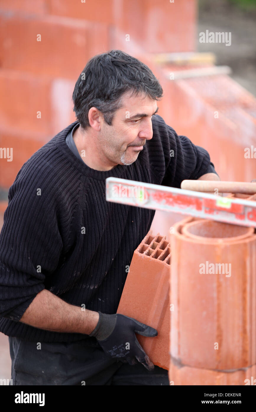 Man working on red bricked wall Stock Photo - Alamy